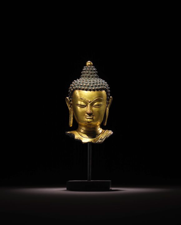 Bonhams : A GILT COPPER ALLOY HEAD OF BUDDHA TIBET, 15TH CENTURY