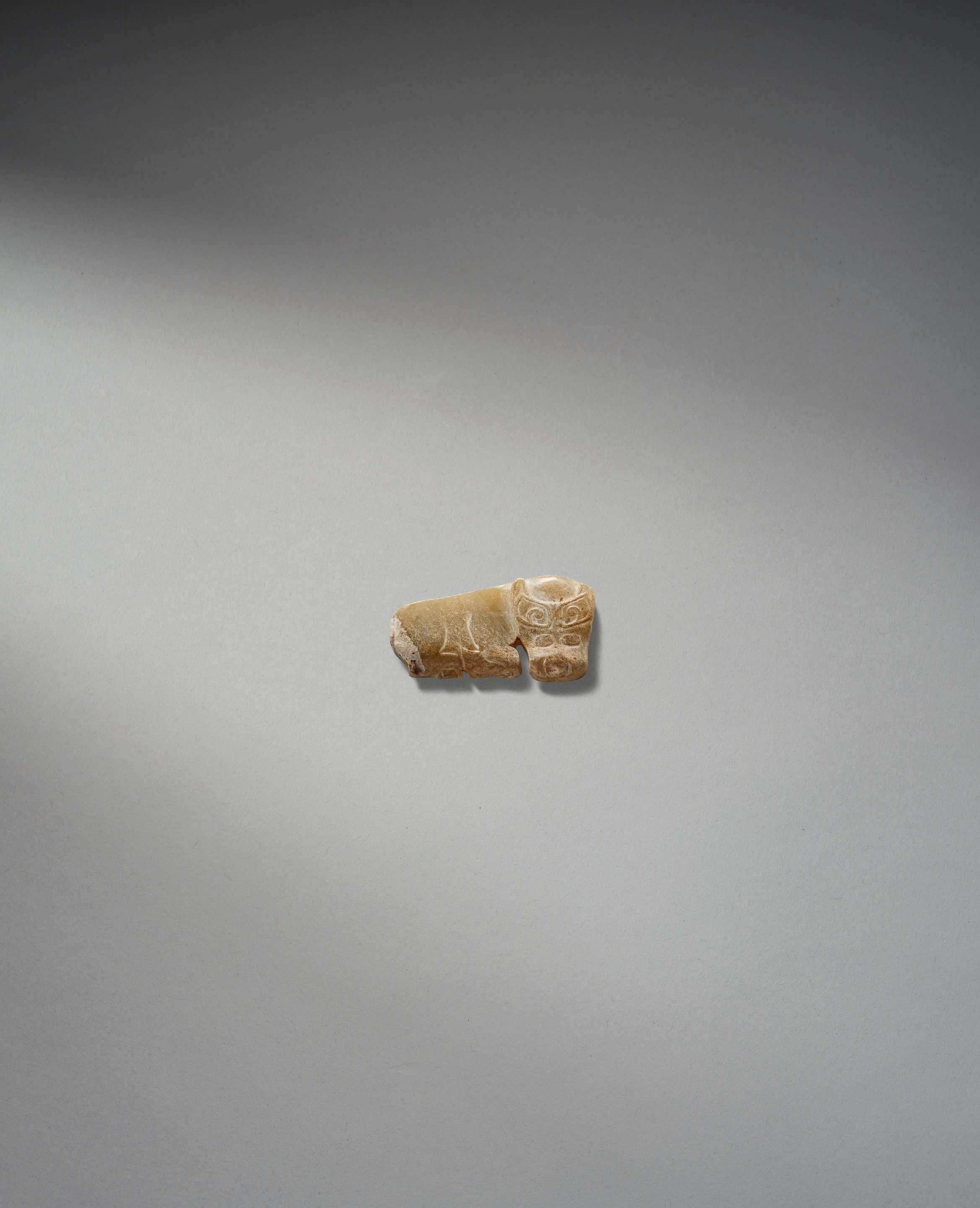 Bonhams : A PALE GREEN JADE 'TIGER' CARVING Late Shang Dynasty